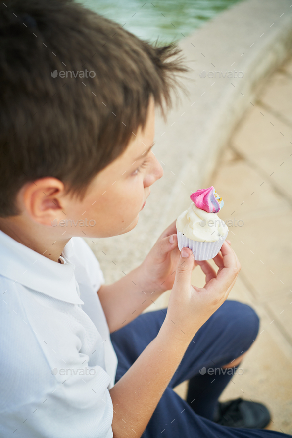 One little boy eating cupcake in park near pond Stock Photo by daniskim