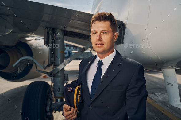 Serene licensed pilot standing by an aircraft Stock Photo by Iakobchuk