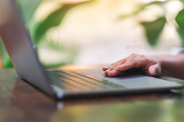 Closeup image of hand using and touching on laptop touchpad on wooden ...