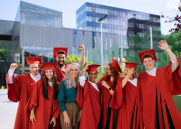University students with teacher celebrating outdoors, looking at ...