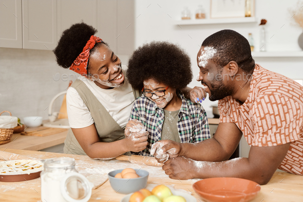Funny young family of three with flour on their faces playing while ...