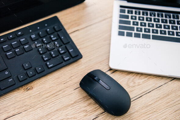 elevated view of computer keyboard, computer mouse and laptop at table ...