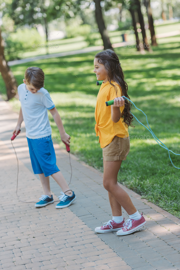 adorable happy kids playing with jumping ropes in park Stock Photo by ...