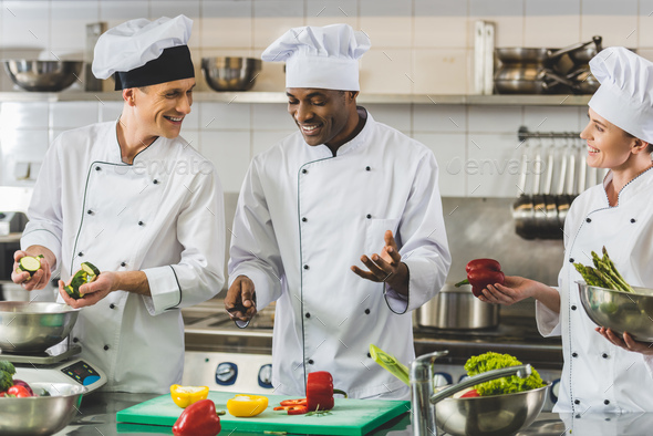 smiling multicultural chefs talking at restaurant kitchen Stock Photo ...