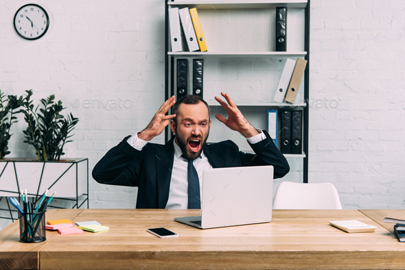 portrait of overworked businessman in suit screaming at workplace with ...