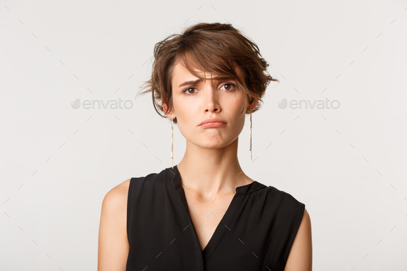 Close-up of sad and tired young woman grimacing, looking miserable ...