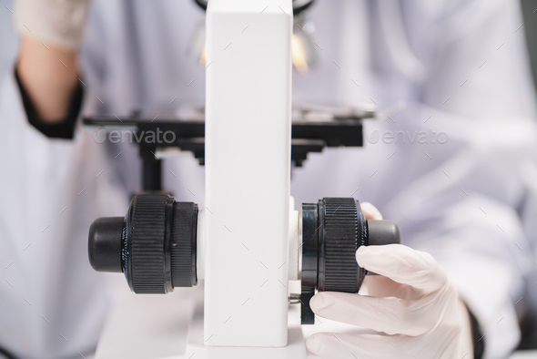scientist looking through scientific microscope lense in laboratory ...