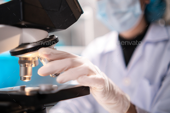 scientist looking through scientific microscope lense in laboratory ...