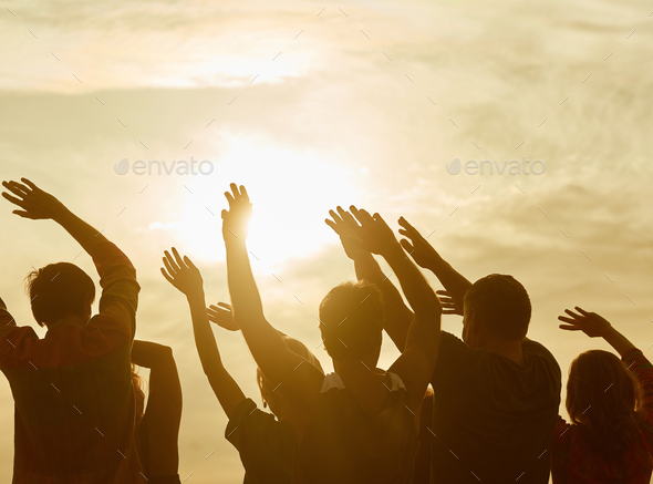 Silhouettes of happy people with hands up. Stock Photo by stockfilmstudio