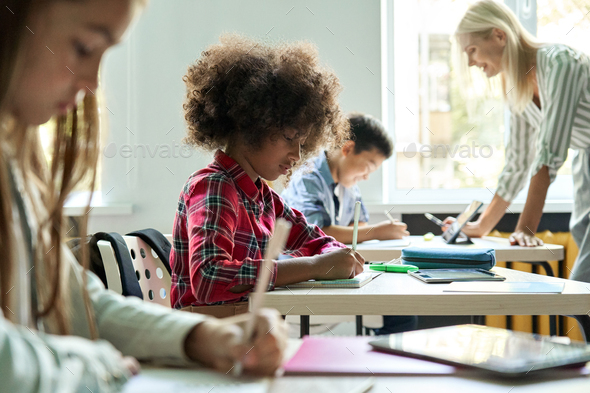 Diverse classmates doing task at lesson studying in classroom with ...