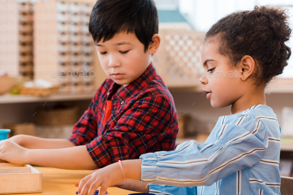 Side view of kids playing educational game during lesson in montessori ...