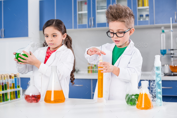 Concentrated little kids in lab coats making experiment in chemical ...