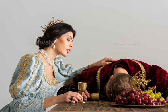 sad queen with crown looking at killed king isolated on grey Stock ...