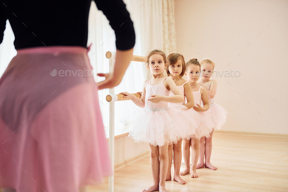 Coach teaches children. Little ballerinas preparing for performance by ...
