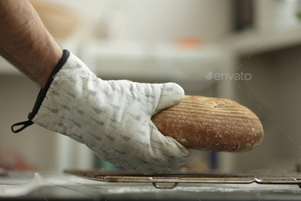 The man holds the freshly baked bread in his hands with gloves Stock ...