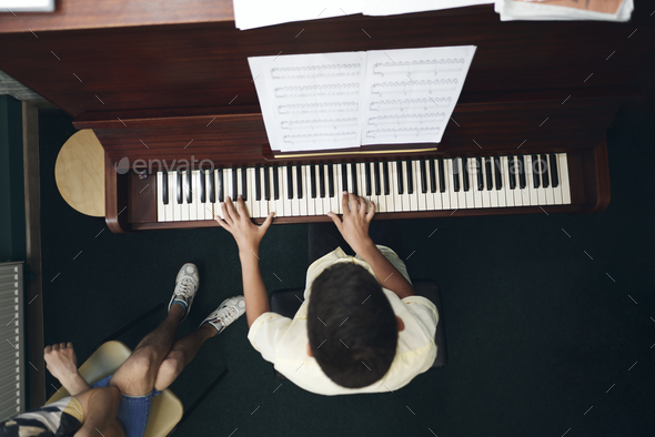 Student playing the piano keyboard at piano lesson Stock Photo by Artranq