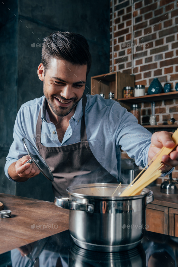handsome young man with apron cooking pasta Stock Photo by ...