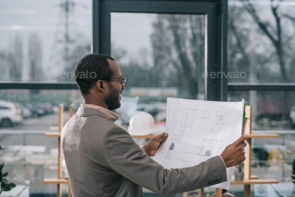 male african american architect looking at building plan in modern ...