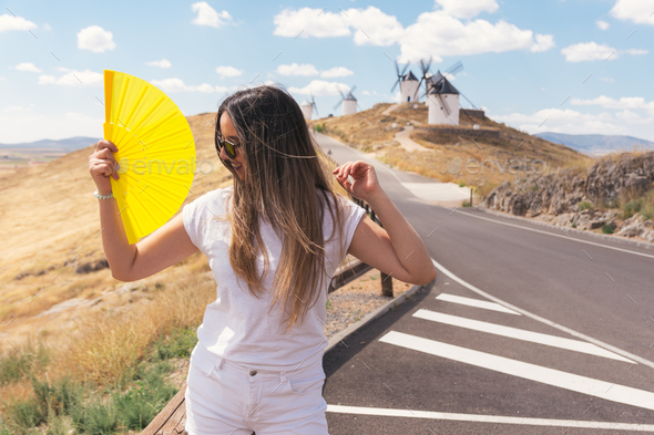 Blonde girl dancing with a yellow fan in her hand fanning herself ...