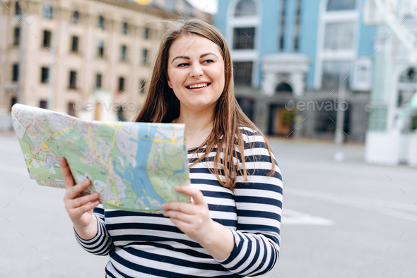 Girl holds a map in her hands. Tourist woman study the map of location ...