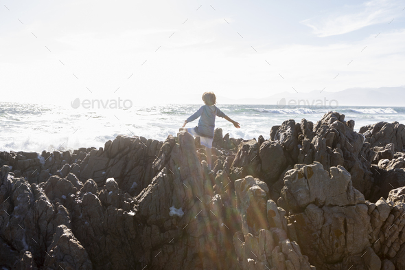 Boy exploring the jagged rocks and rock pools on the Atlantic Ocean ...