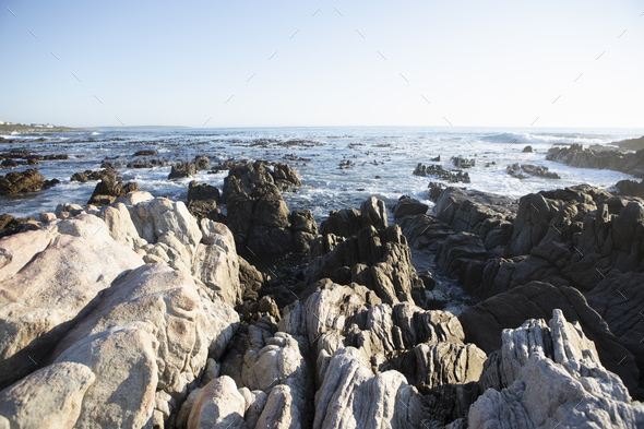 Jagged rocks ridges leading out into the sea, and waves breaking on ...