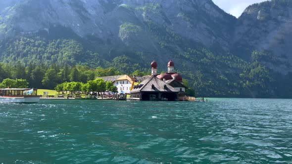 Tracking shot of Royal idyllic Königssee in with beautiful old church ...