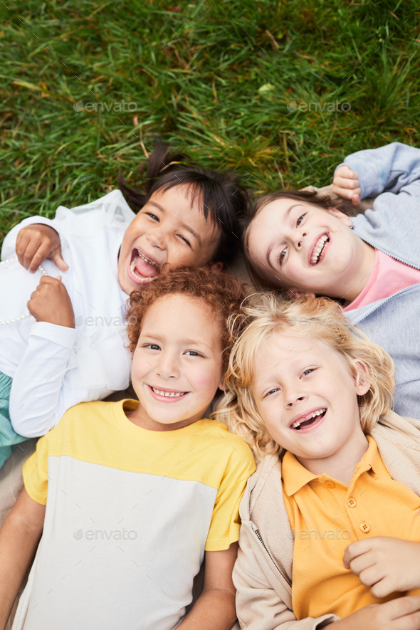 Smiling Children Lying on Grass Stock Photo by seventyfourimages ...