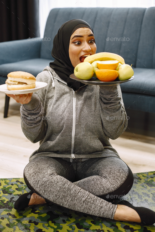 Arab woman choosing between healthy and unhealthy eating Stock Photo by ...