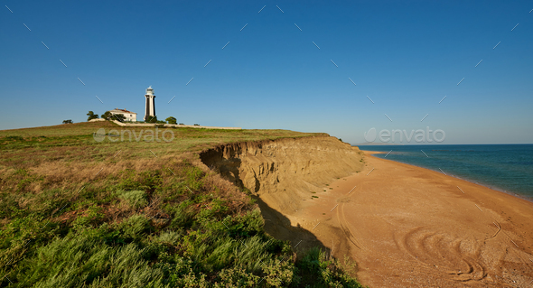 Desolate beach with a lighthouse in the ocean Stock Photo by viktoriian