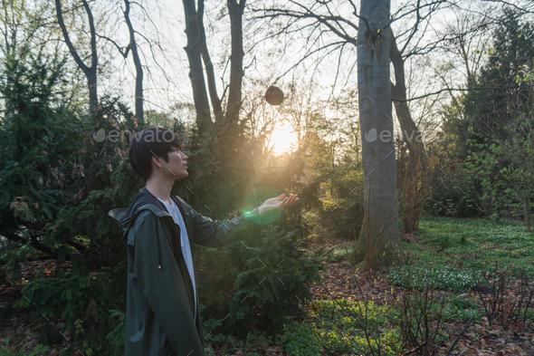 Man throwing a ball vertically and standing in woods Stock Photo by ...