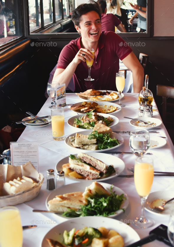 Man sitting at a dinner table drinking Stock Photo by scopioimages