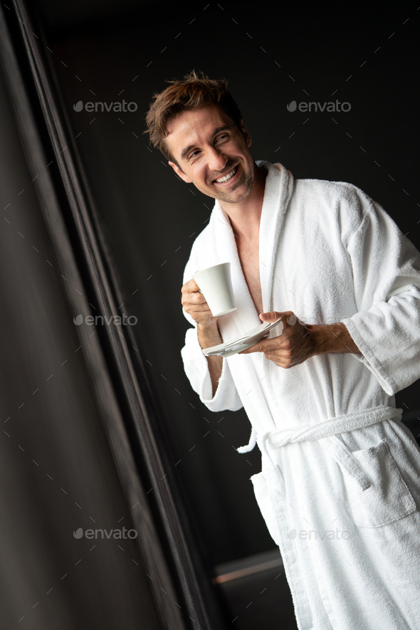 Handsome, muscular, young man drinking his morning coffee in a hotel ...