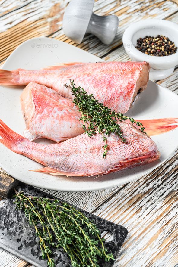 Whole raw red snapper fish on a plate. White wooden background. Top ...