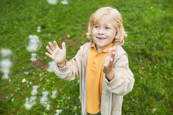Smiling Boy Catching Bubbles Stock Photo by seventyfourimages | PhotoDune