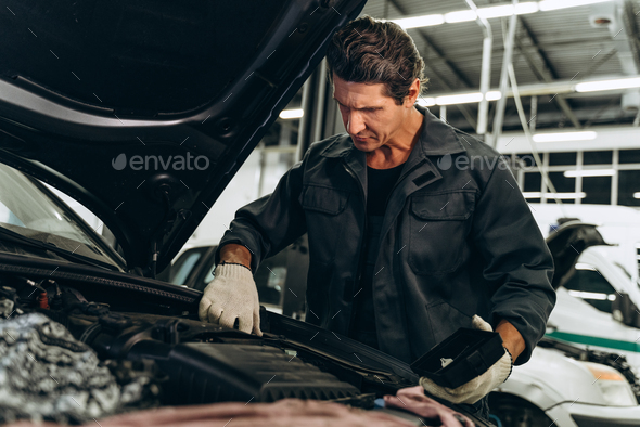 Waist up portrait view of the serious car mechanic in his repair shop ...