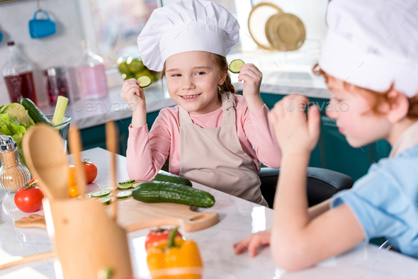 cute little children in chef hats having fun while cooking together in ...