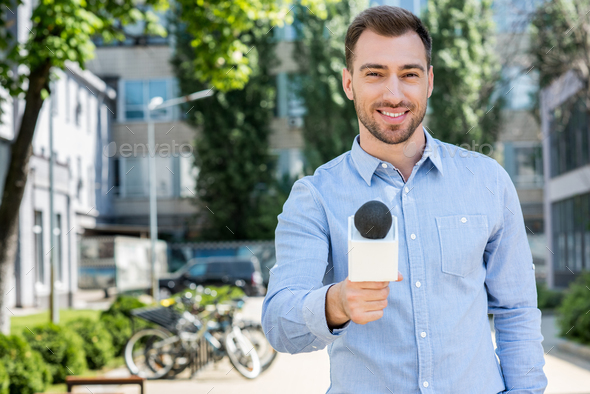 smiling male news reporter taking interview with microphone Stock Photo ...
