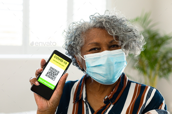 Happy senior african american woman wearing face mask showing covid qr ...