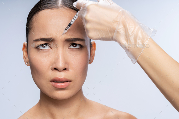 Pretty young lady is receiving injection head-on Stock Photo by Iakobchuk