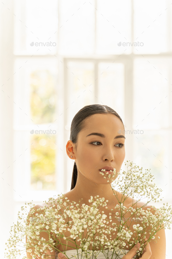 Sad calm lady posing with bouquet in studio Stock Photo by Iakobchuk