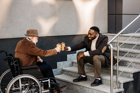 Senior Disabled Man In Wheelchair And African American Man Drinking