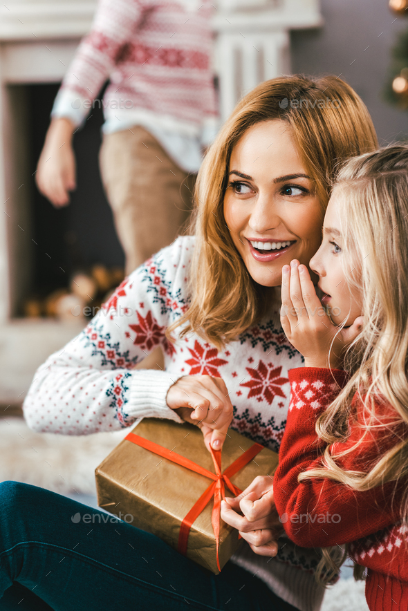 mother and daughter gossiping and unpacking gift together while sitting ...