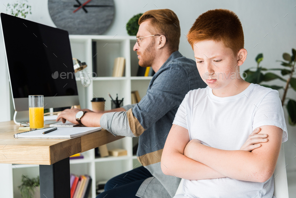 father using computer and sad son looking down at home Stock Photo by ...