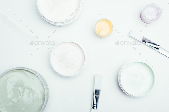 flat lay with different clay masks in containers and brushes isolated ...