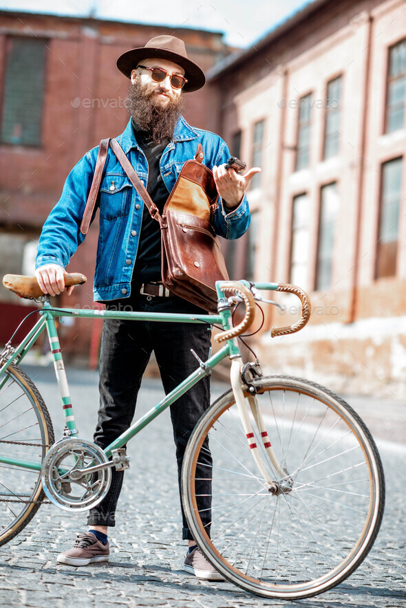 Stylish man with retro bicycle and gun outdoors Stock Photo by RossHelen