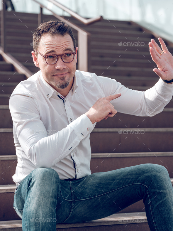 Smiling businessman pointing at watch Stock Photo by ADDICTIVE_STOCK