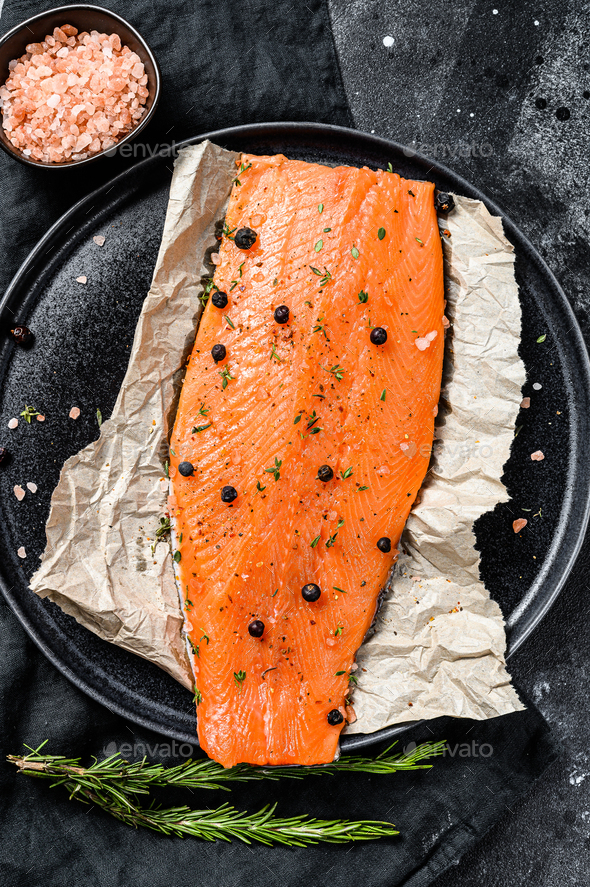 Fresh sea trout fillet with salt, herbs and spices. Black background ...