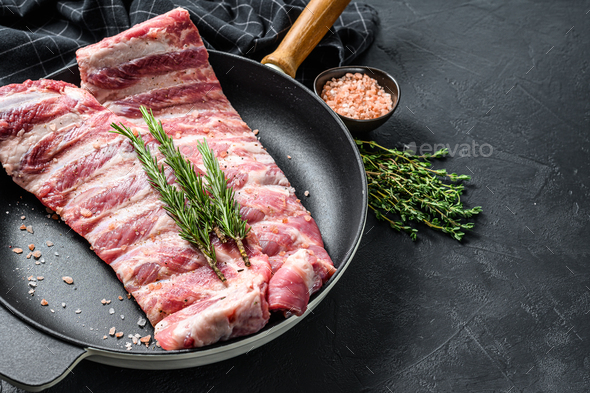 Rack of uncooked raw pork spare ribs seasoned with spices in a pan ...