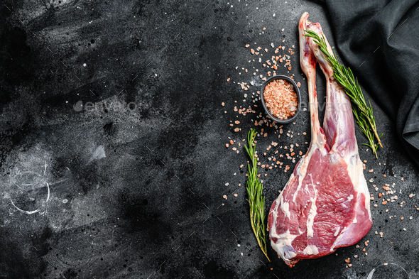Raw goat leg with salt and garlic. Farm meat. Black background. Top ...